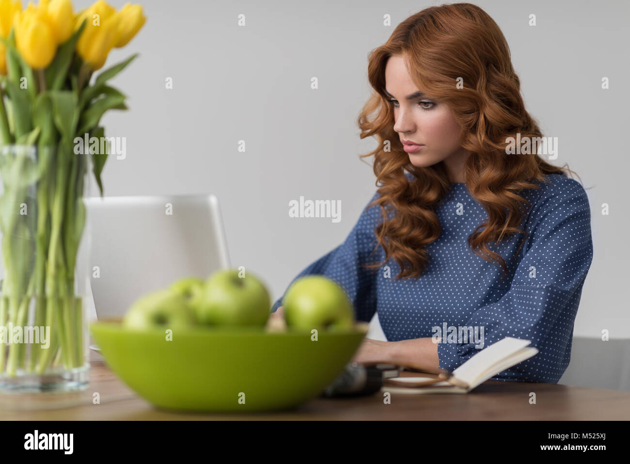 Closeup portrait of a beautiful young redhead woman working using ...
