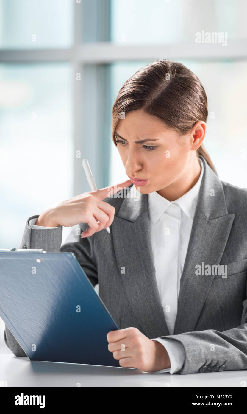 Front view of business woman looking over papers on clipboard at her ...