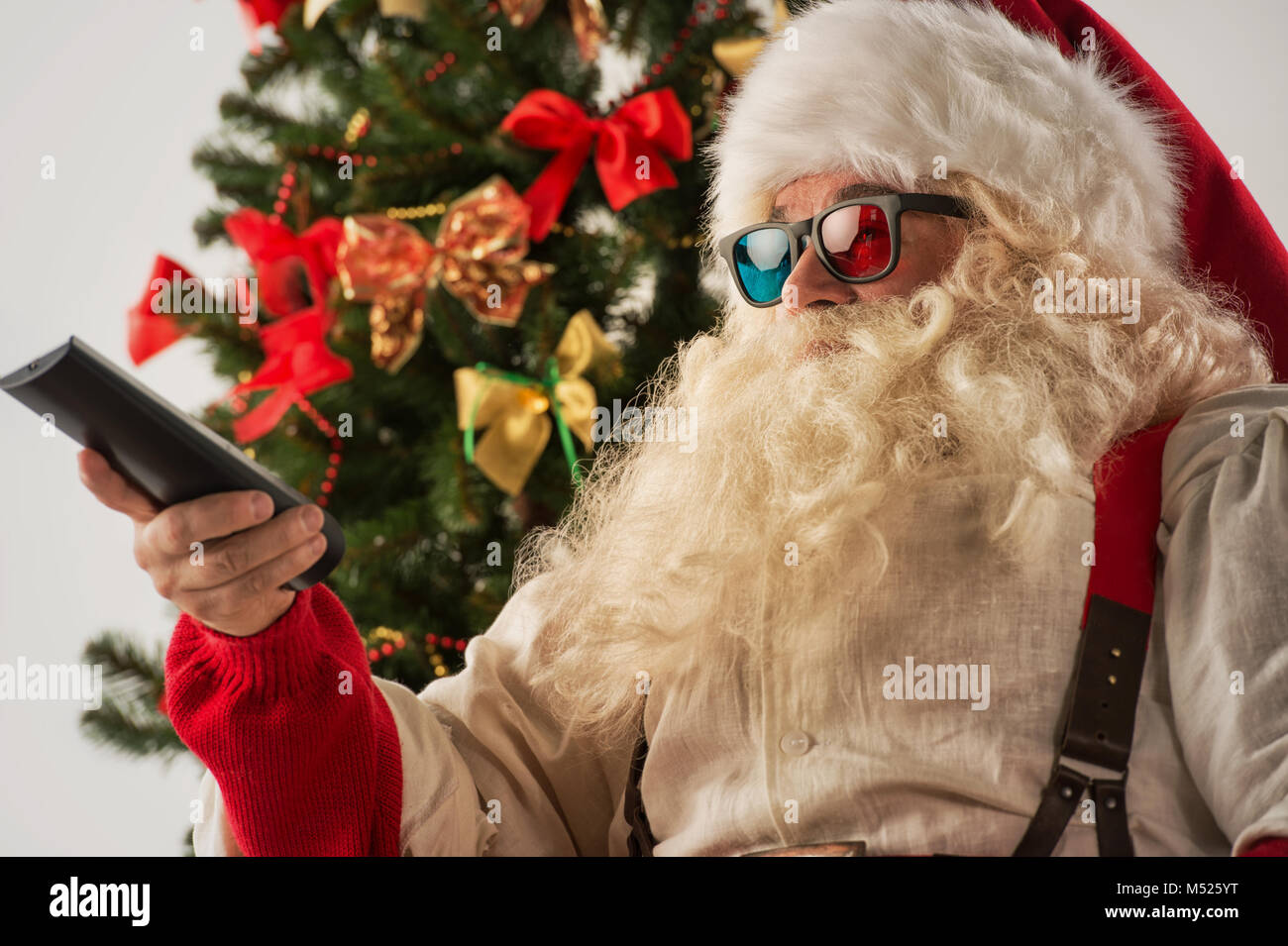 Santa Claus sitting in rocking chair near Christmas Tree at home and ...