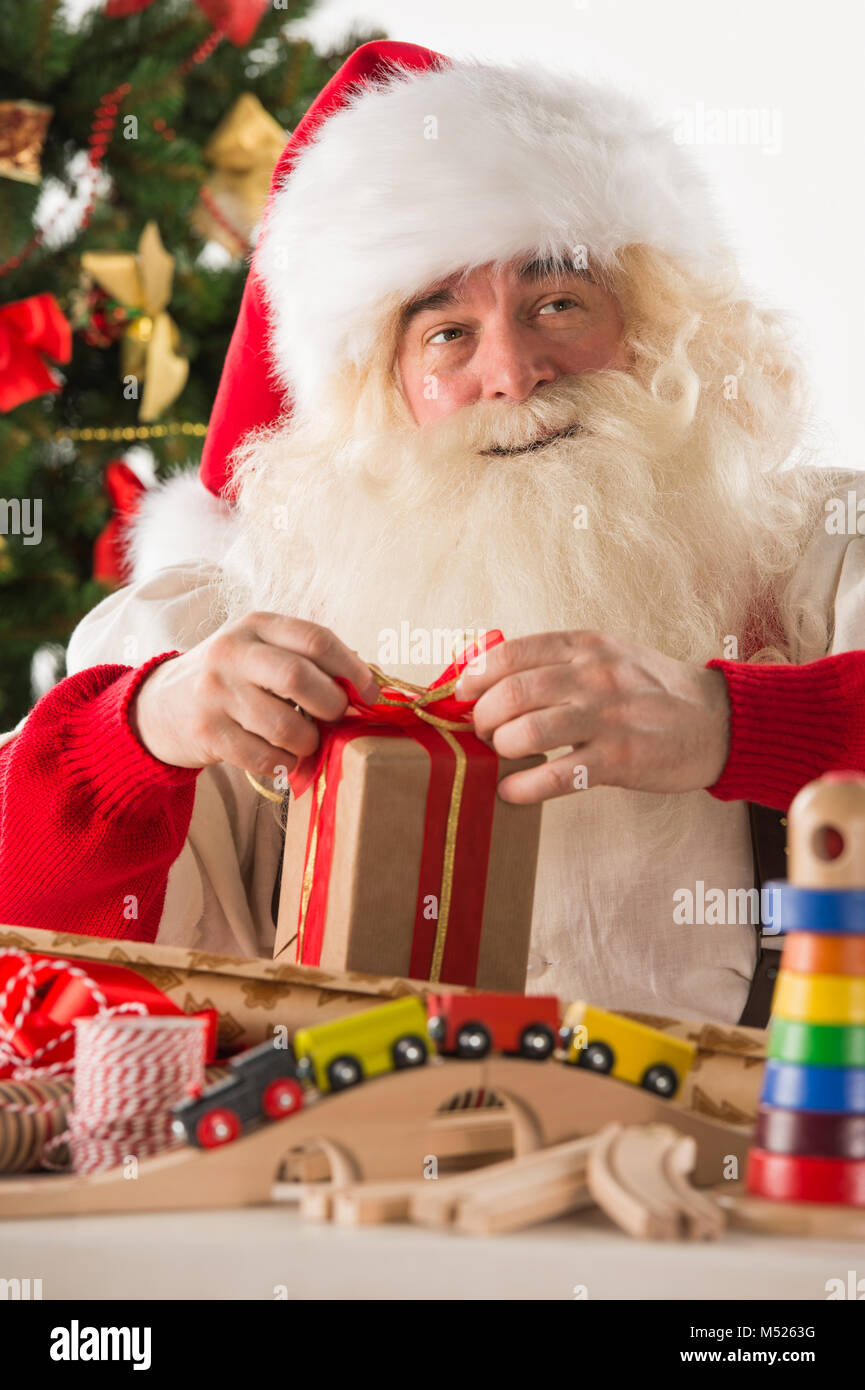 Santa Claus working - preparing and wrapping christmas gifts, toys ...