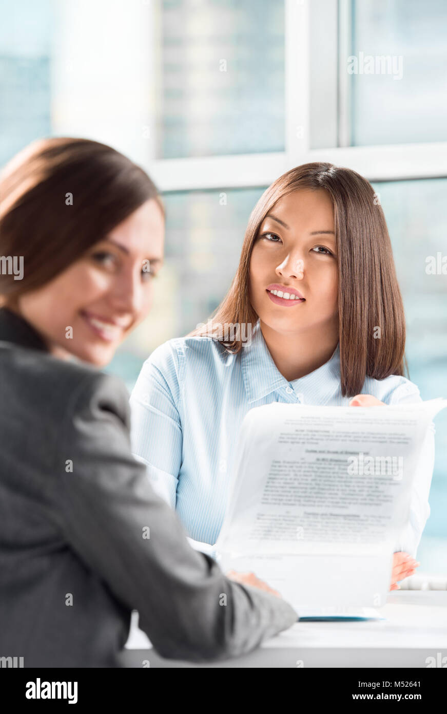 Two business women talking and signing contract at office Stock Photo ...