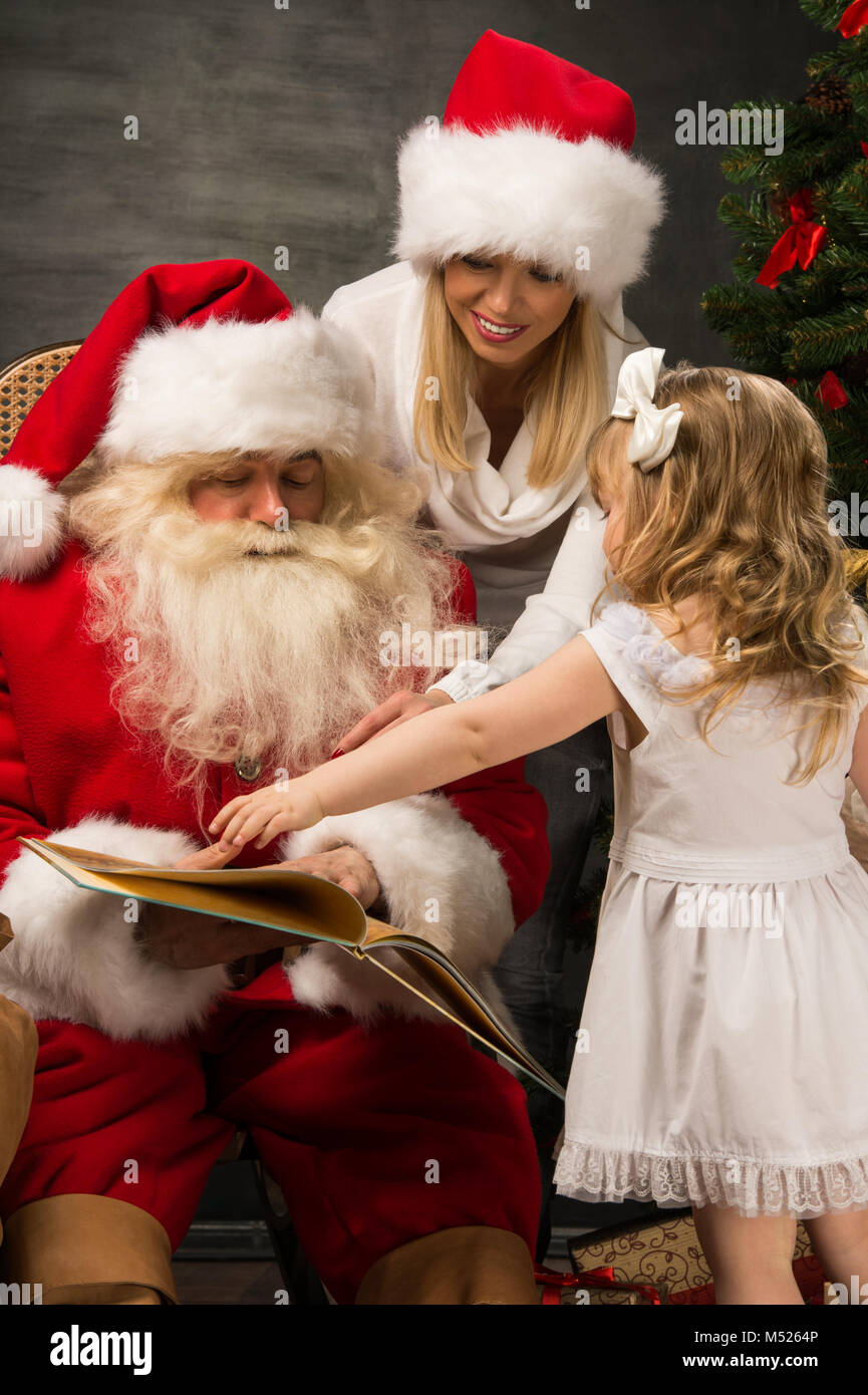 Santa Claus sitting at home with family - little girl and her mother ...