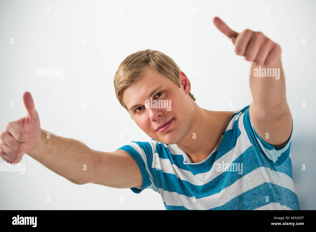 Closeup of good looking young man gesturing thumbs up sign while ...