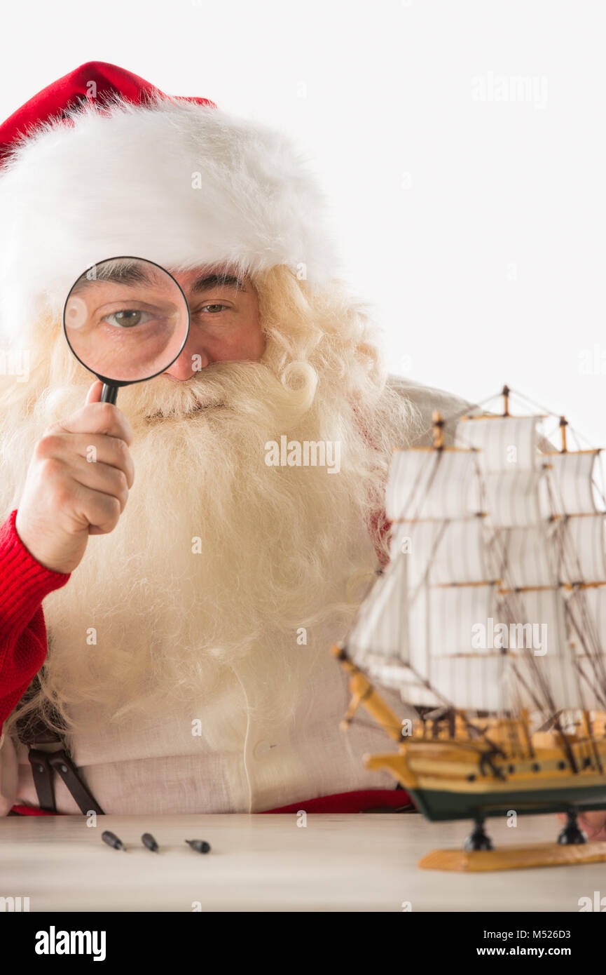 Santa Claus making toys. Looking at camera through the magnifying glass ...