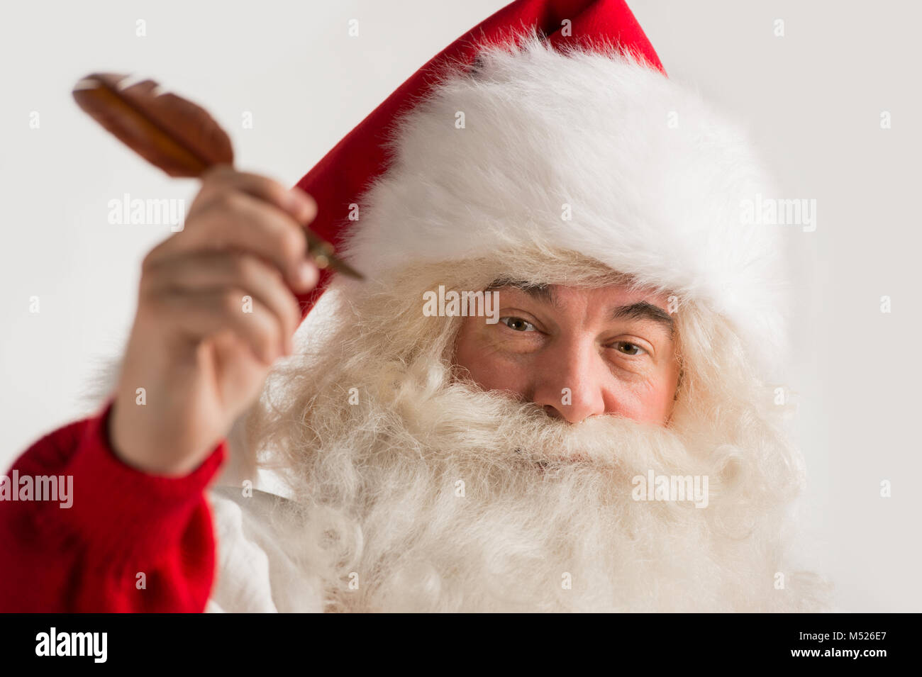 Santa Claus holding feather pen in his arm and writing Stock Photo - Alamy
