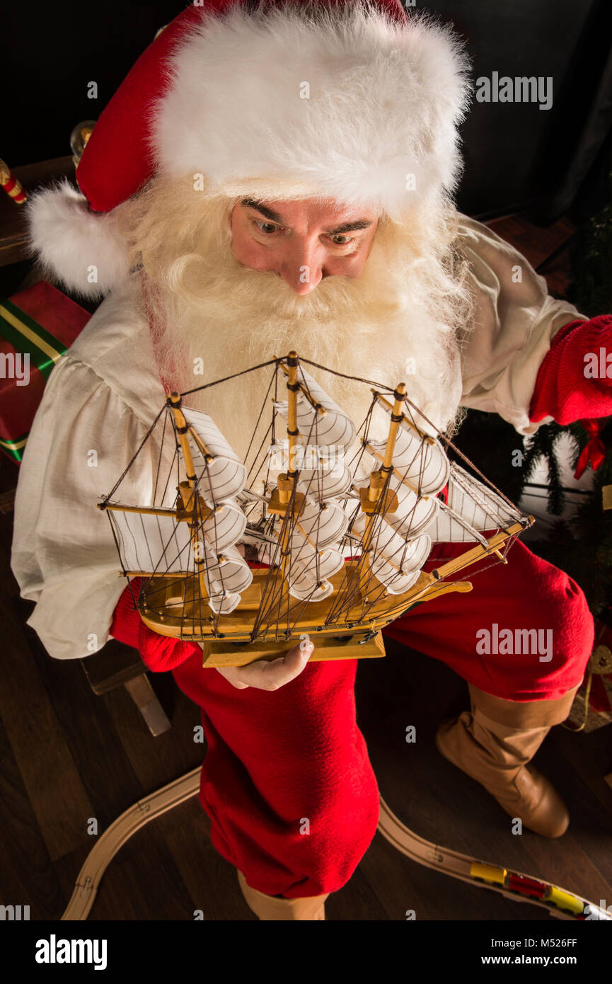 Santa Claus at home playing with new toys near Christmas Tree indoors ...