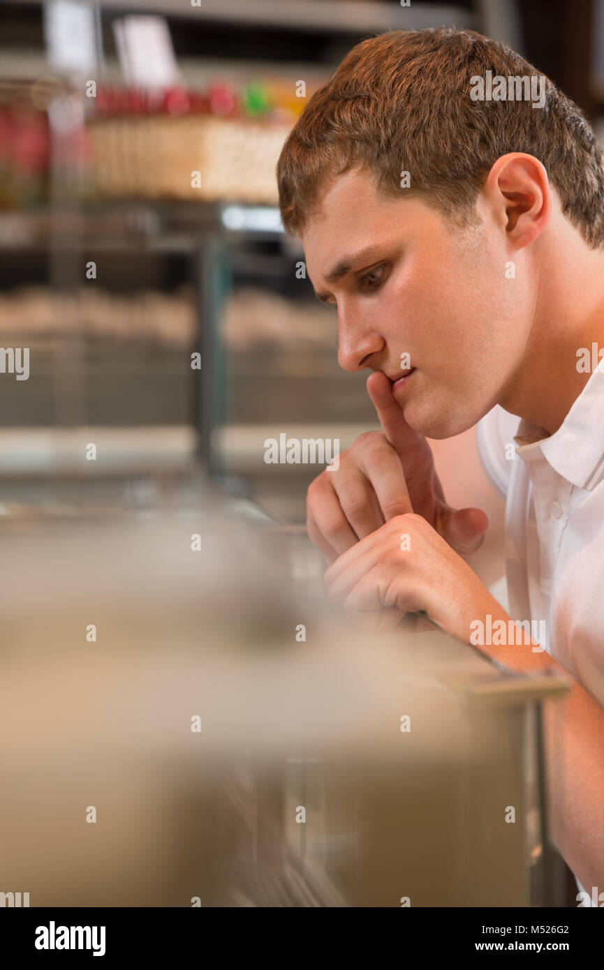 Handsome young man standing near supermarket showcase full of different ...