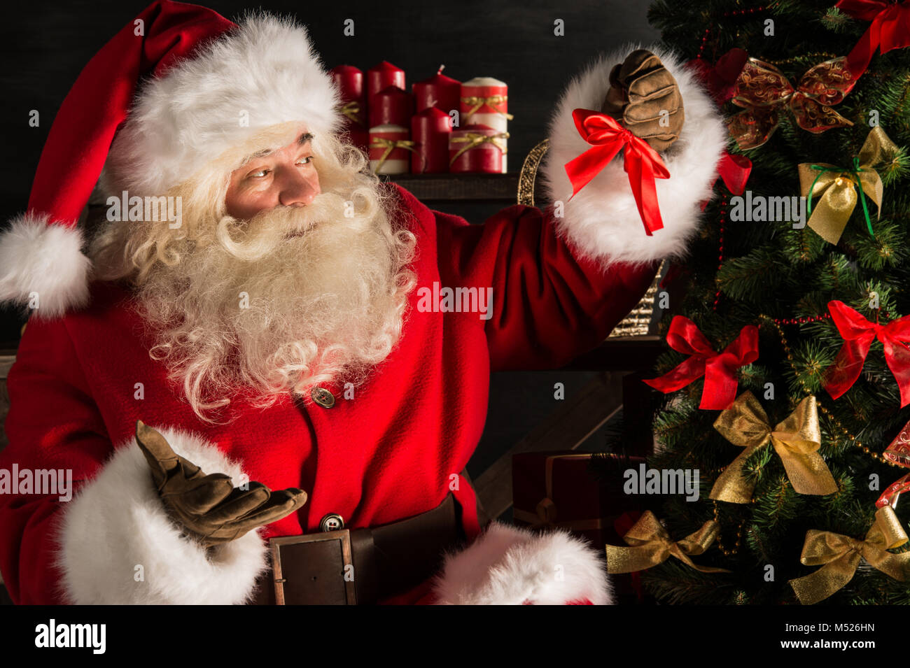 Santa Claus decorating Christmas tree in dark room Stock Photo - Alamy
