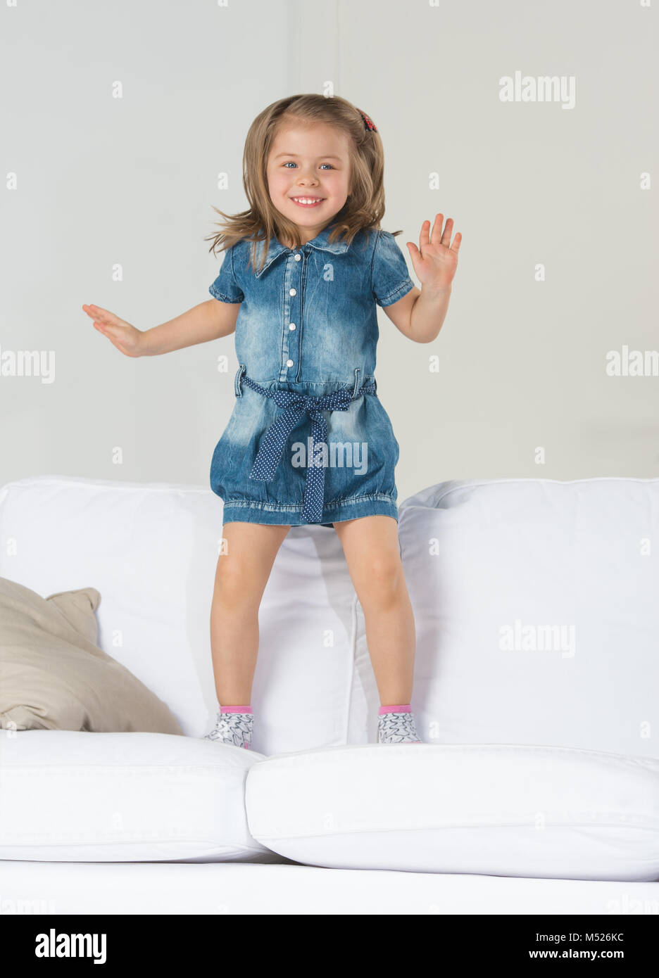 Adorable little girl jumping at home on sofa Stock Photo - Alamy