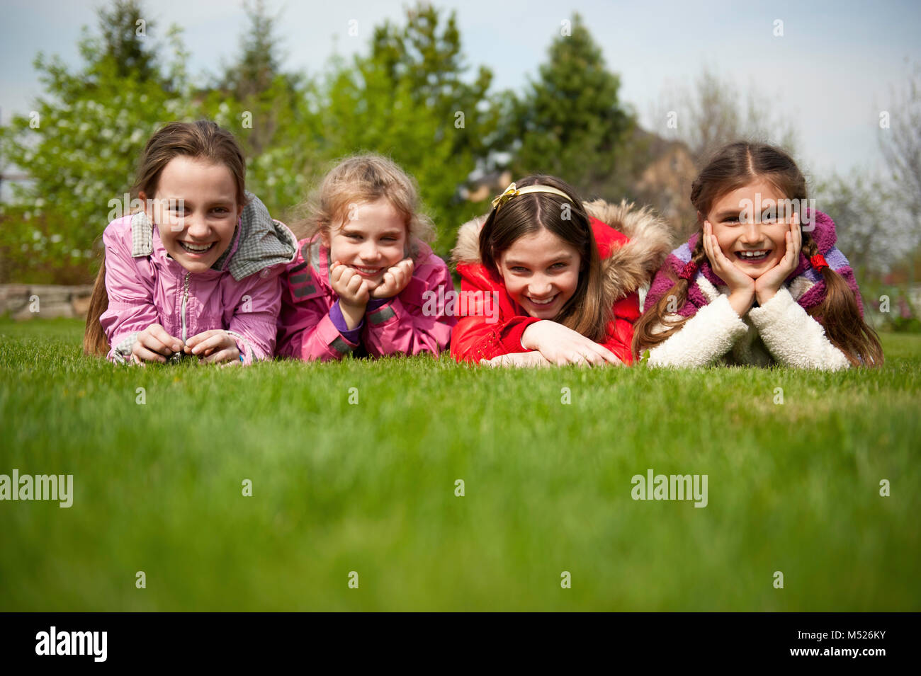 Smiley girls lying on the grass portrait Stock Photo - Alamy