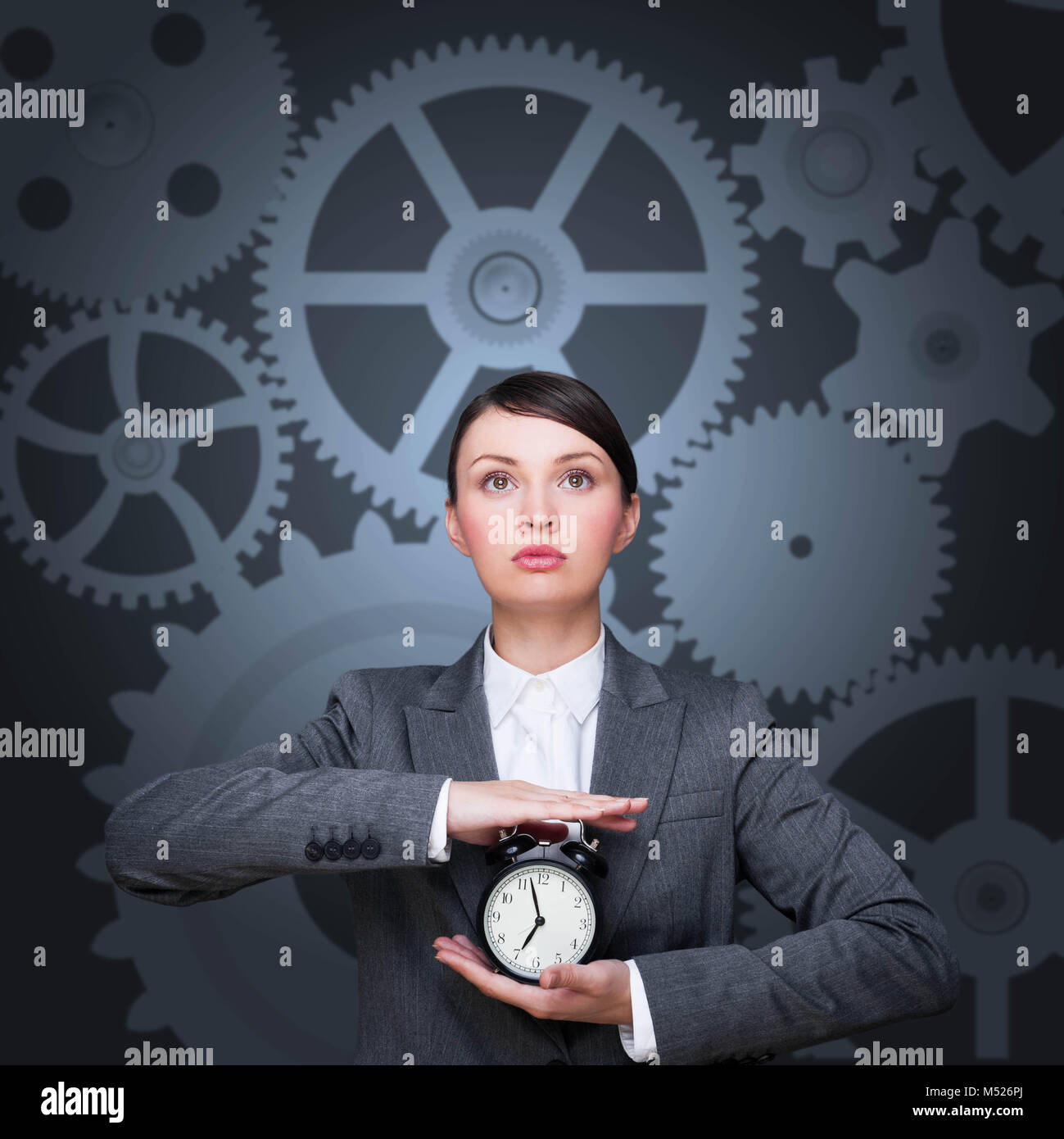 Young businesswoman holding a clock with clockwork background Stock ...
