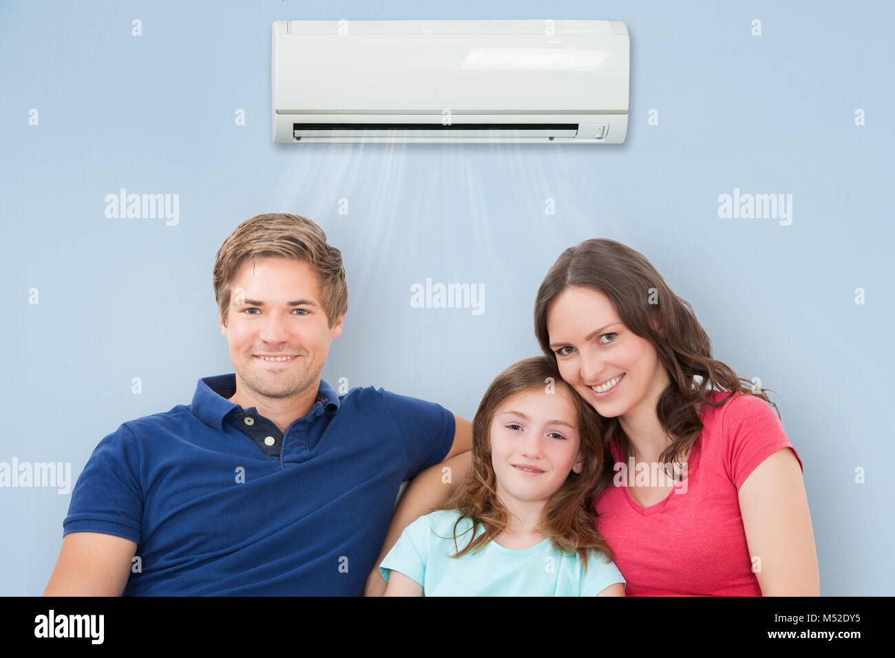 Happy Family Sitting On Sofa Under Air Conditioning At Home Stock Photo - Alamy