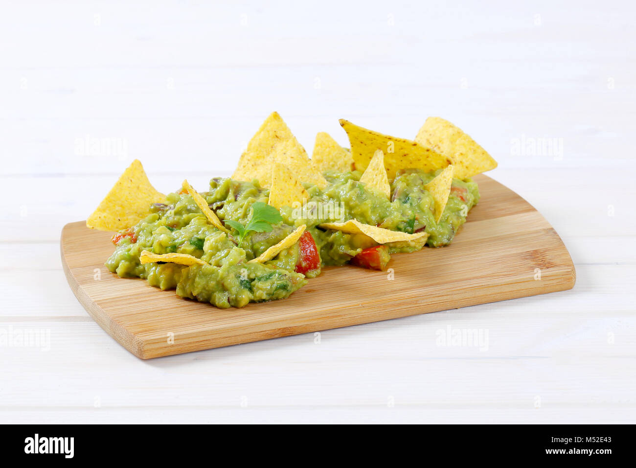guacamole with corn tortilla chips on wooden cutting board Stock Photo ...