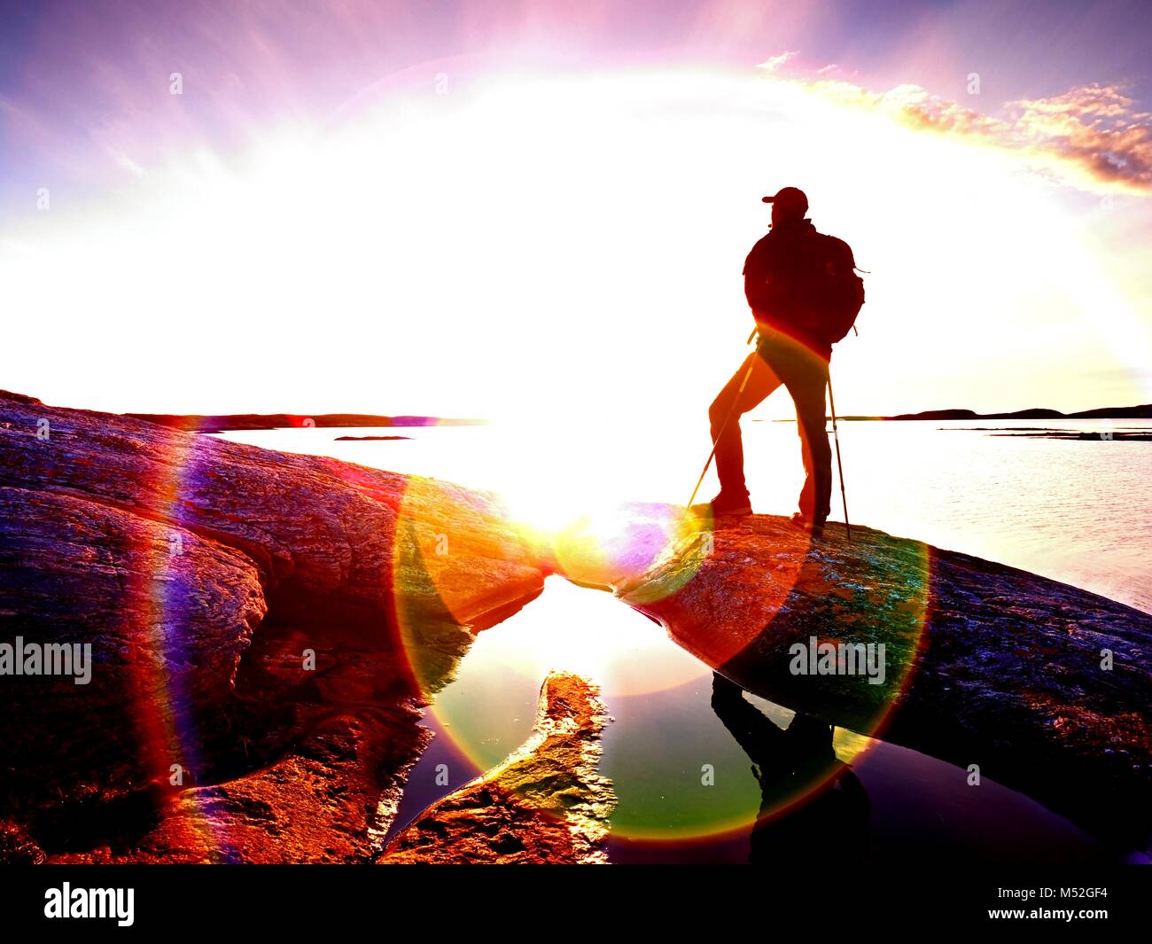 Man, sea and sun at horizon. Traveler on rocky cliff above sea enjoy ...