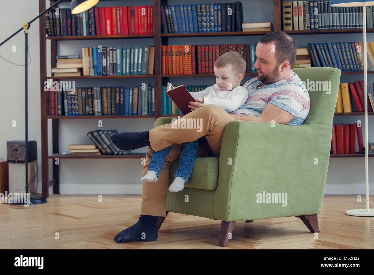 Picture of father reading book to son sitting in chair Stock Photo - Alamy