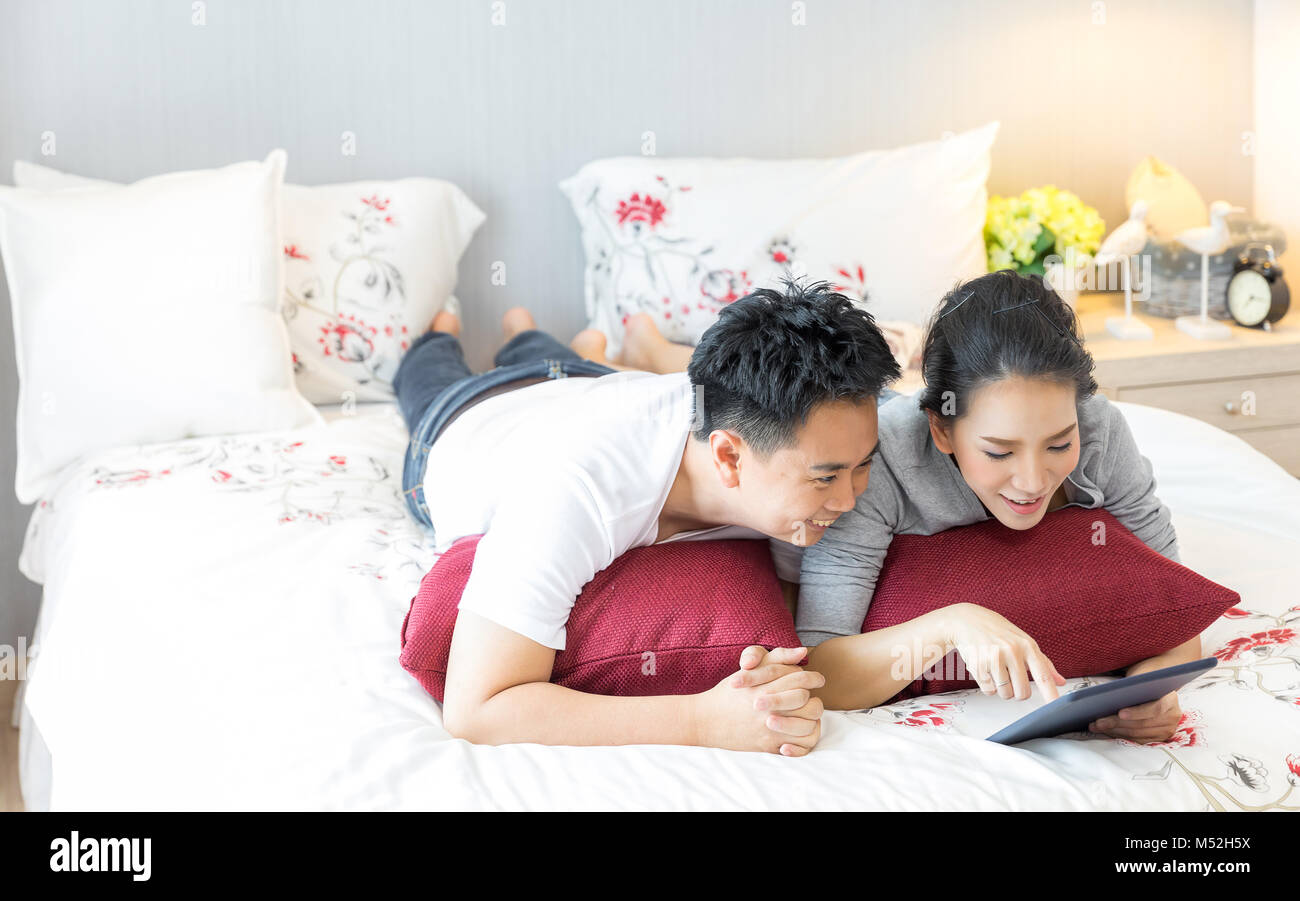 Couples lying using tablet on bed Stock Photo - Alamy