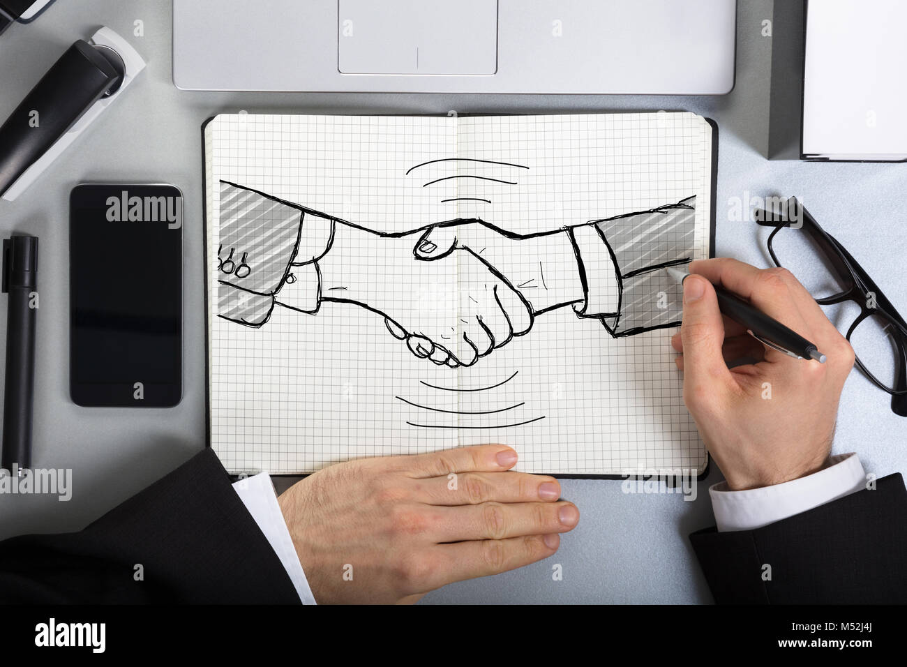 Close-up Of A Business Person Drawing Handshake Concept In Grid Book On ...