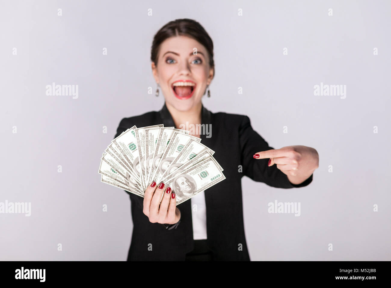 Well dressed woman pointing finger at cash, dollar. Studio shot, indoor ...