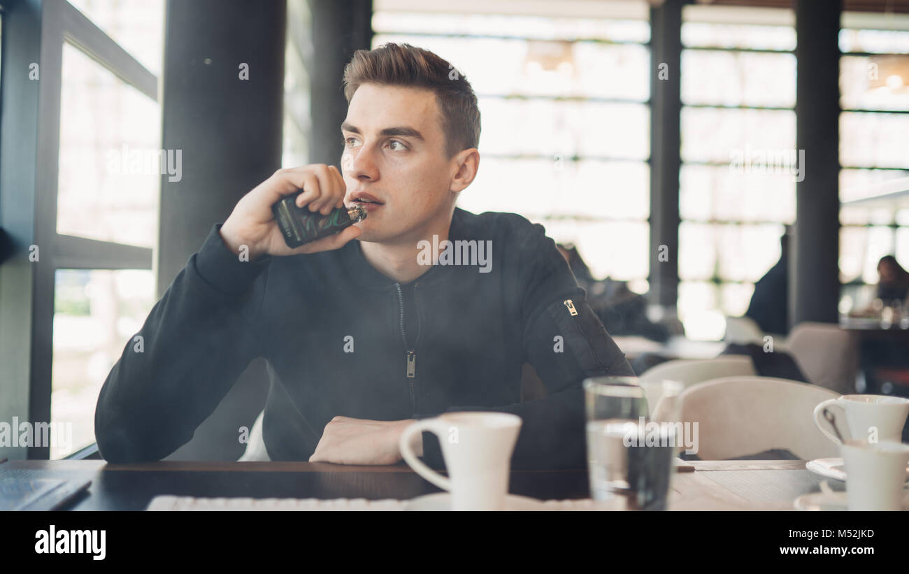 Young man vaping in closed public space.Smoking electronic cigarette in ...