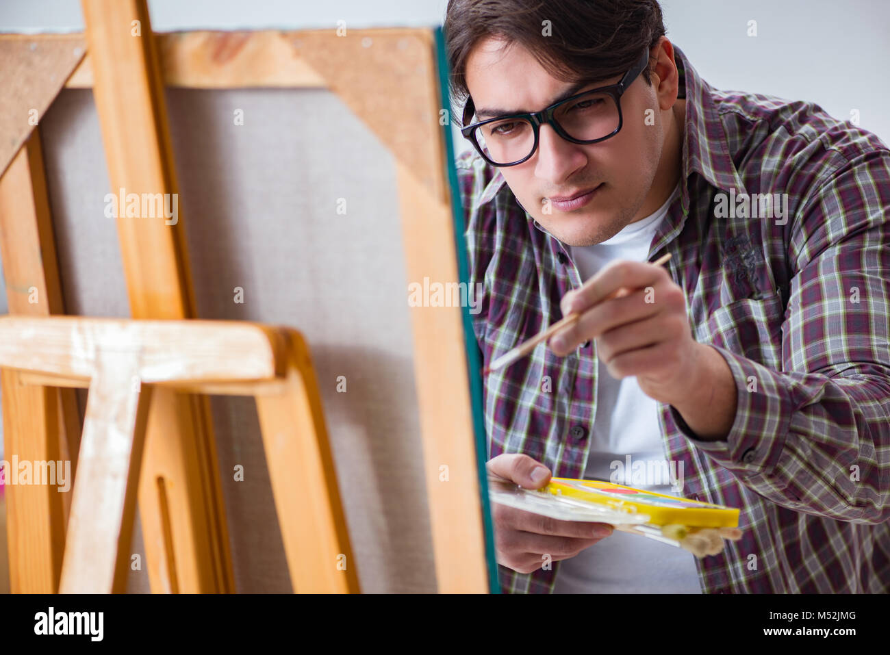 Young male artist drawing pictures in bright studio Stock Photo - Alamy
