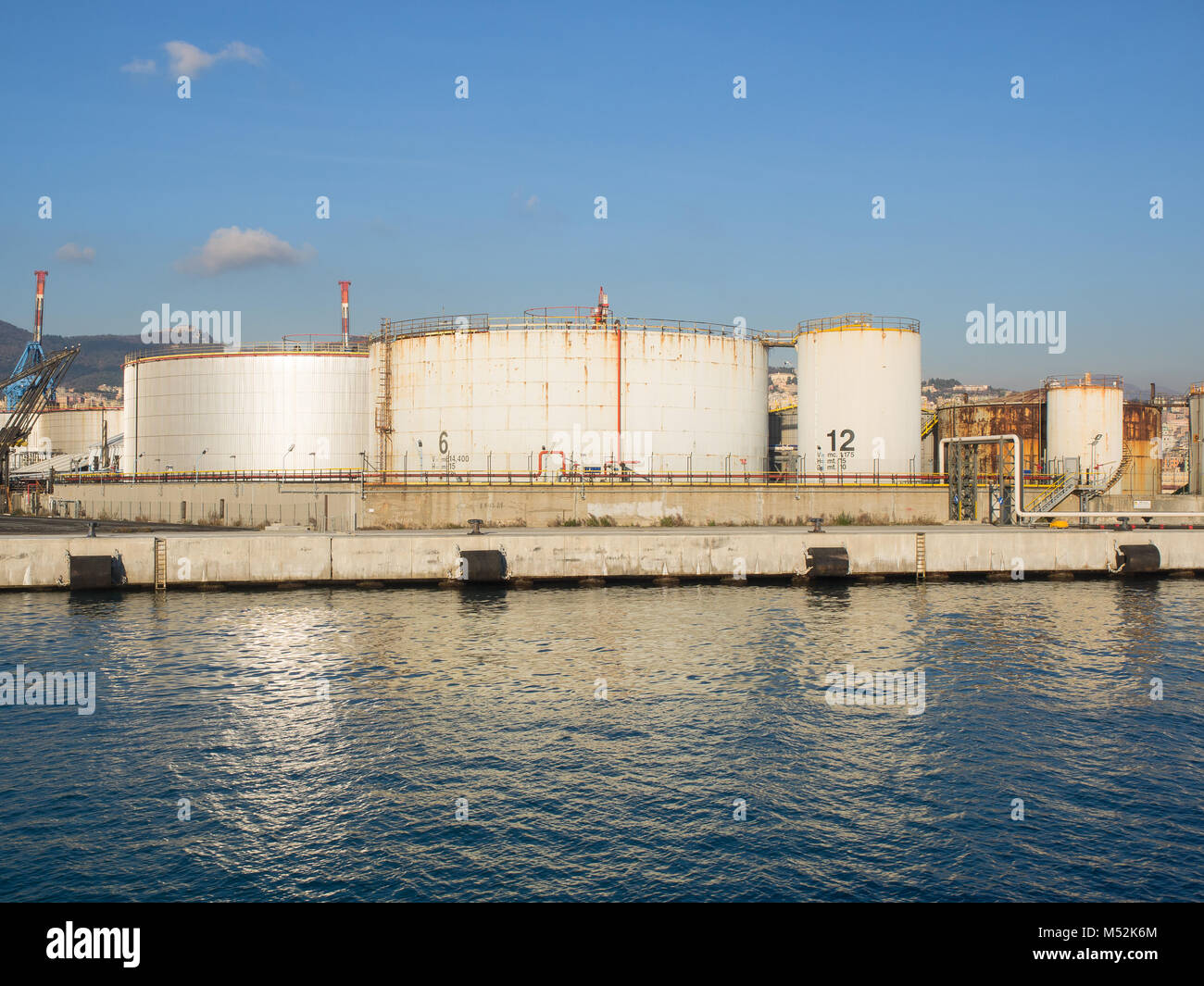 big oil tanks in a petrochemical port, reflecting in the sea water ...