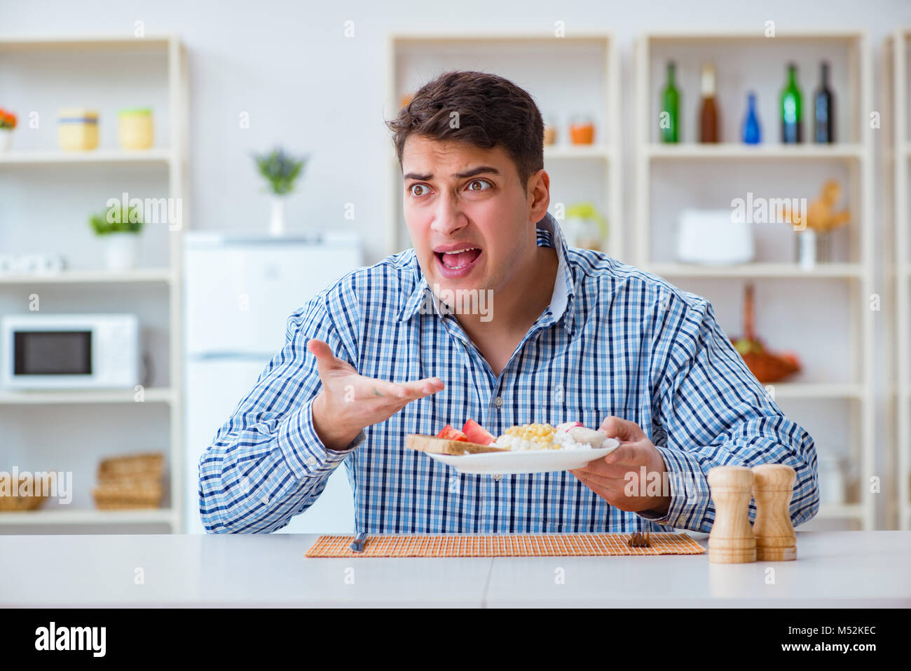 Young husband eating tasteless food at home for lunch Stock Photo - Alamy