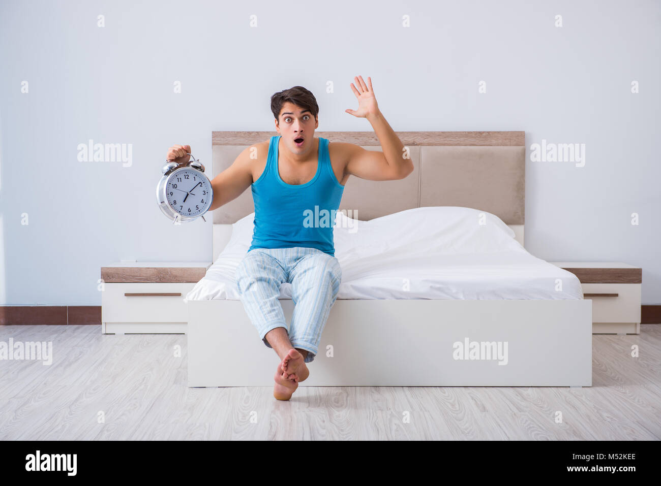Young man waking up in bed Stock Photo - Alamy