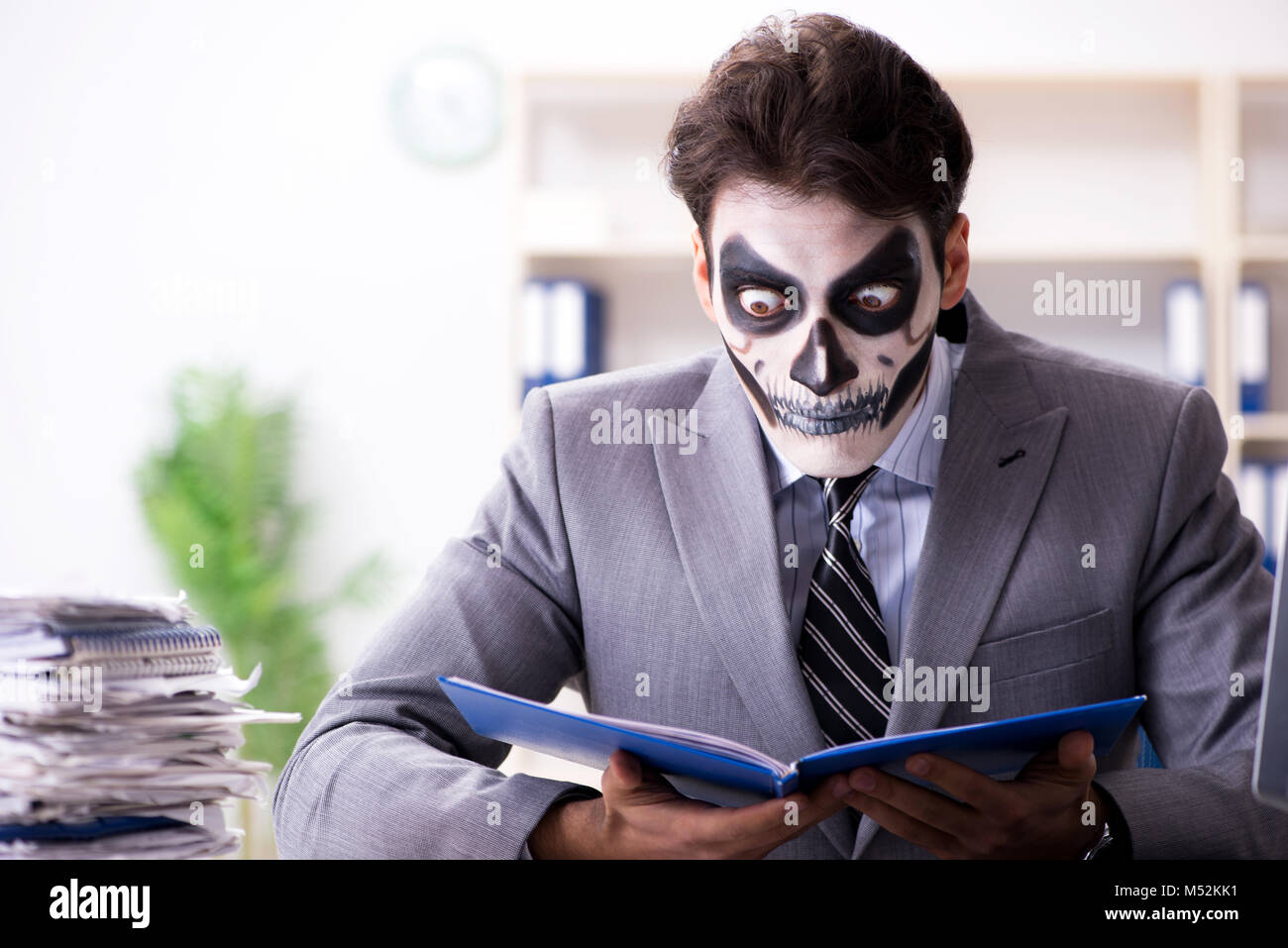 Businessman with scary face mask working in office Stock Photo - Alamy