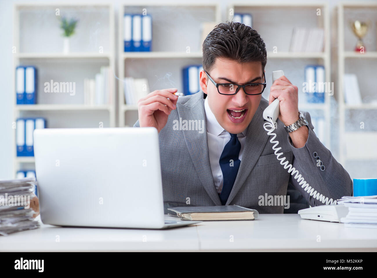 Businessman smoking in office at work Stock Photo - Alamy