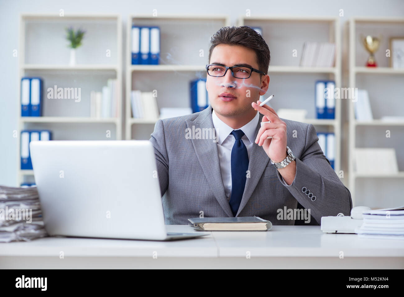 Businessman smoking in office at work Stock Photo - Alamy