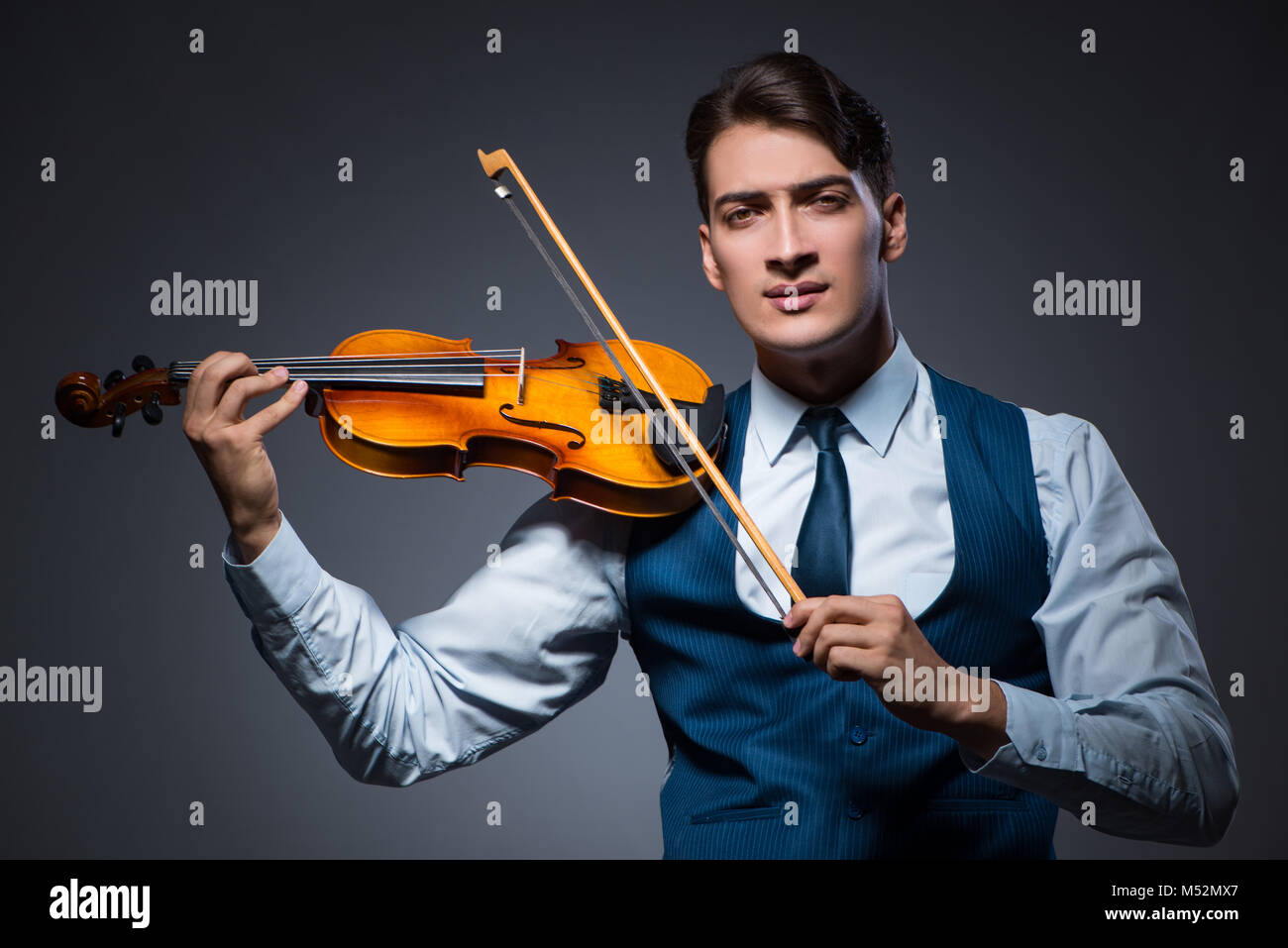 Young man playing violin in dark room Stock Photo - Alamy