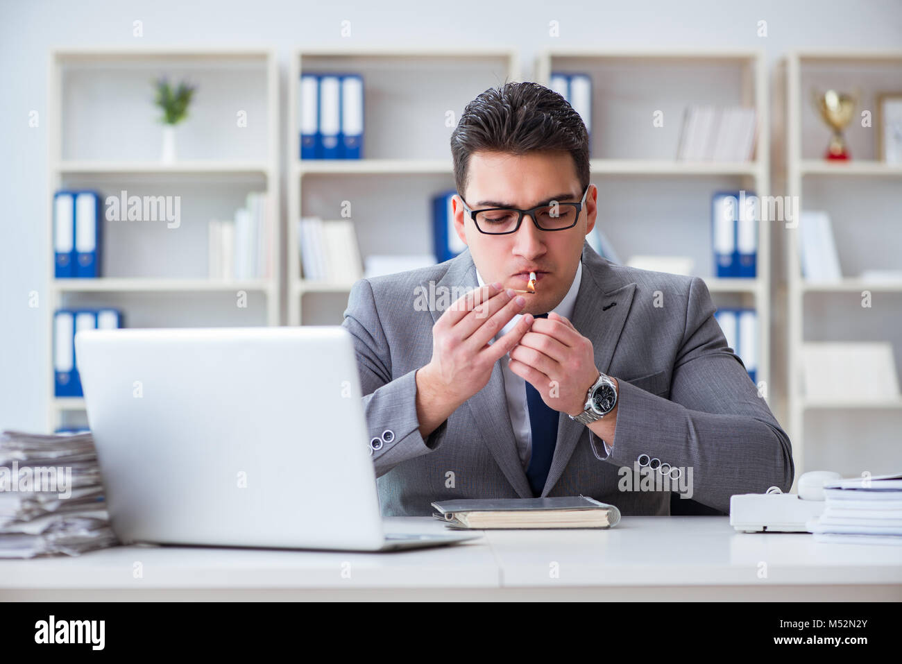 Businessman smoking in office at work Stock Photo - Alamy