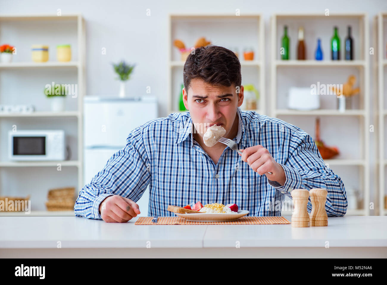 Man eating tasteless food at home for lunch Stock Photo - Alamy