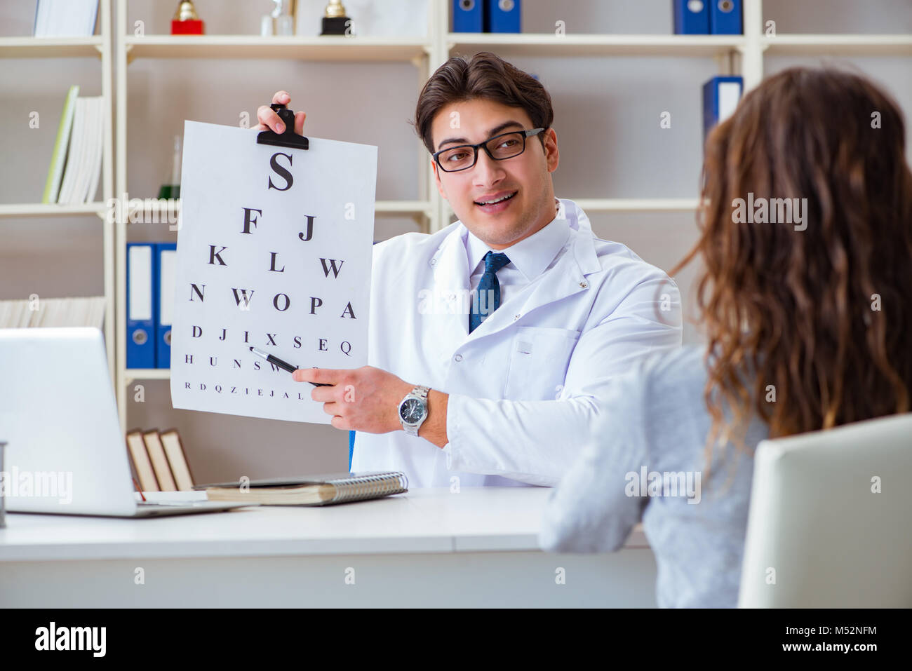 Doctor optician with letter chart conducting an eye test check Stock ...