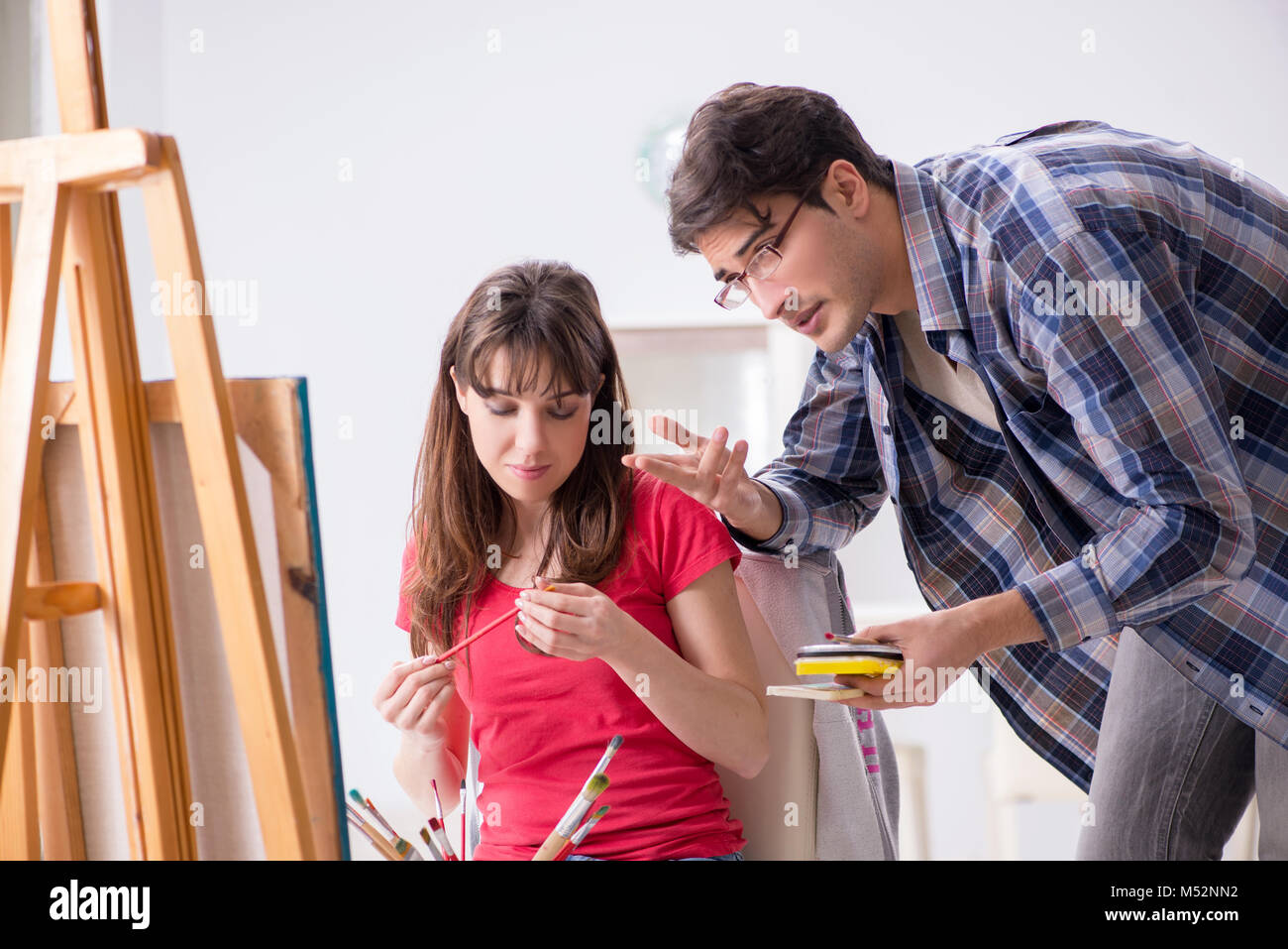 Artist coaching student in painting class in studio Stock Photo - Alamy