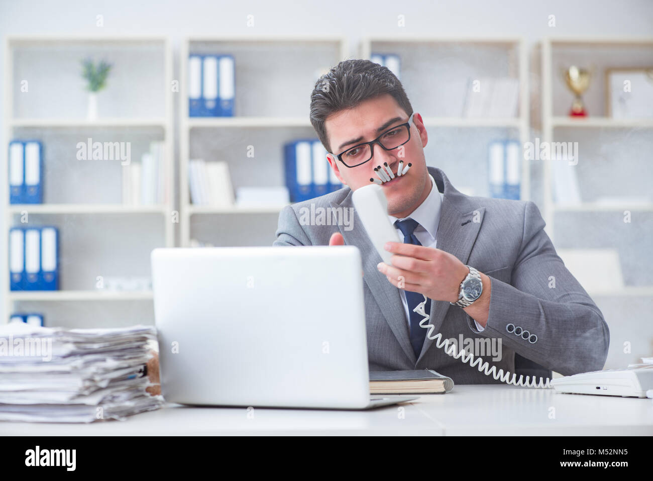 Businessman smoking in office at work Stock Photo - Alamy
