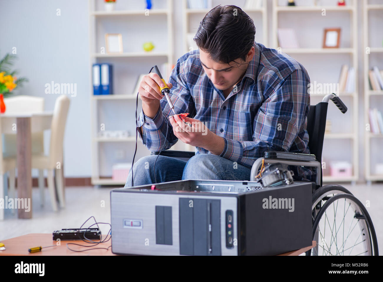 The disabled man on wheelchair repairing computer Stock Photo - Alamy