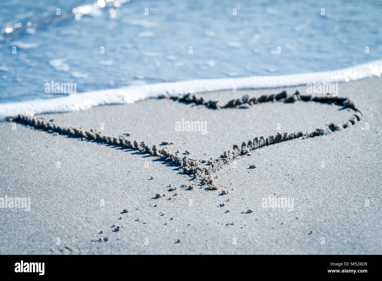 Heart drawn on the sand of the beach and blue sea waves with foam Stock ...