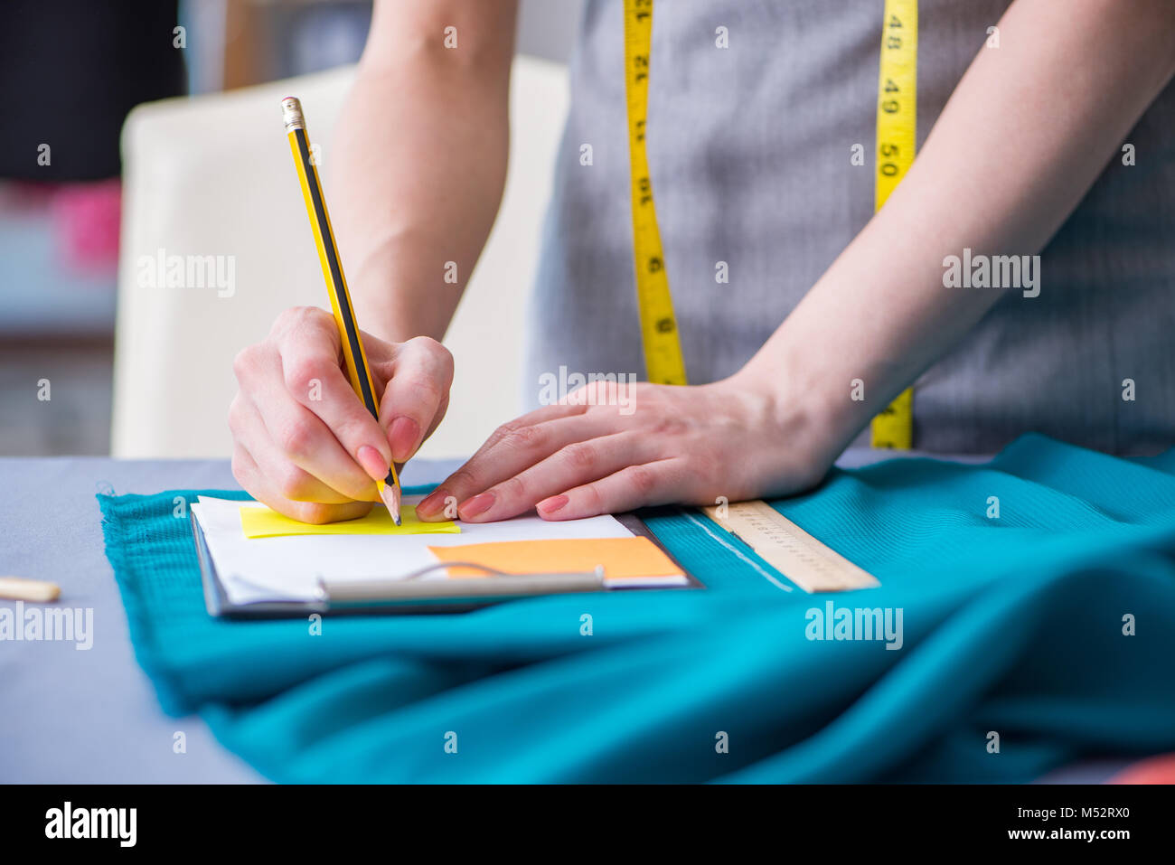 Woman tailor working on a clothing sewing stitching measuring fa Stock ...