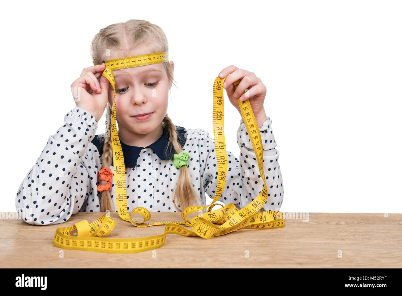 Little girl measuring tape measure with her head sitting at a wooden ...
