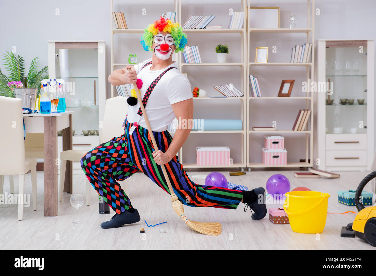 Funny clown doing cleaning at home Stock Photo - Alamy