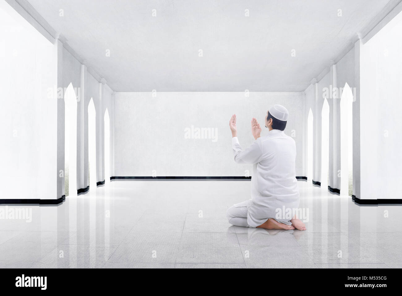 Back view of asian muslim man kneeling and praying to god in the mosque ...
