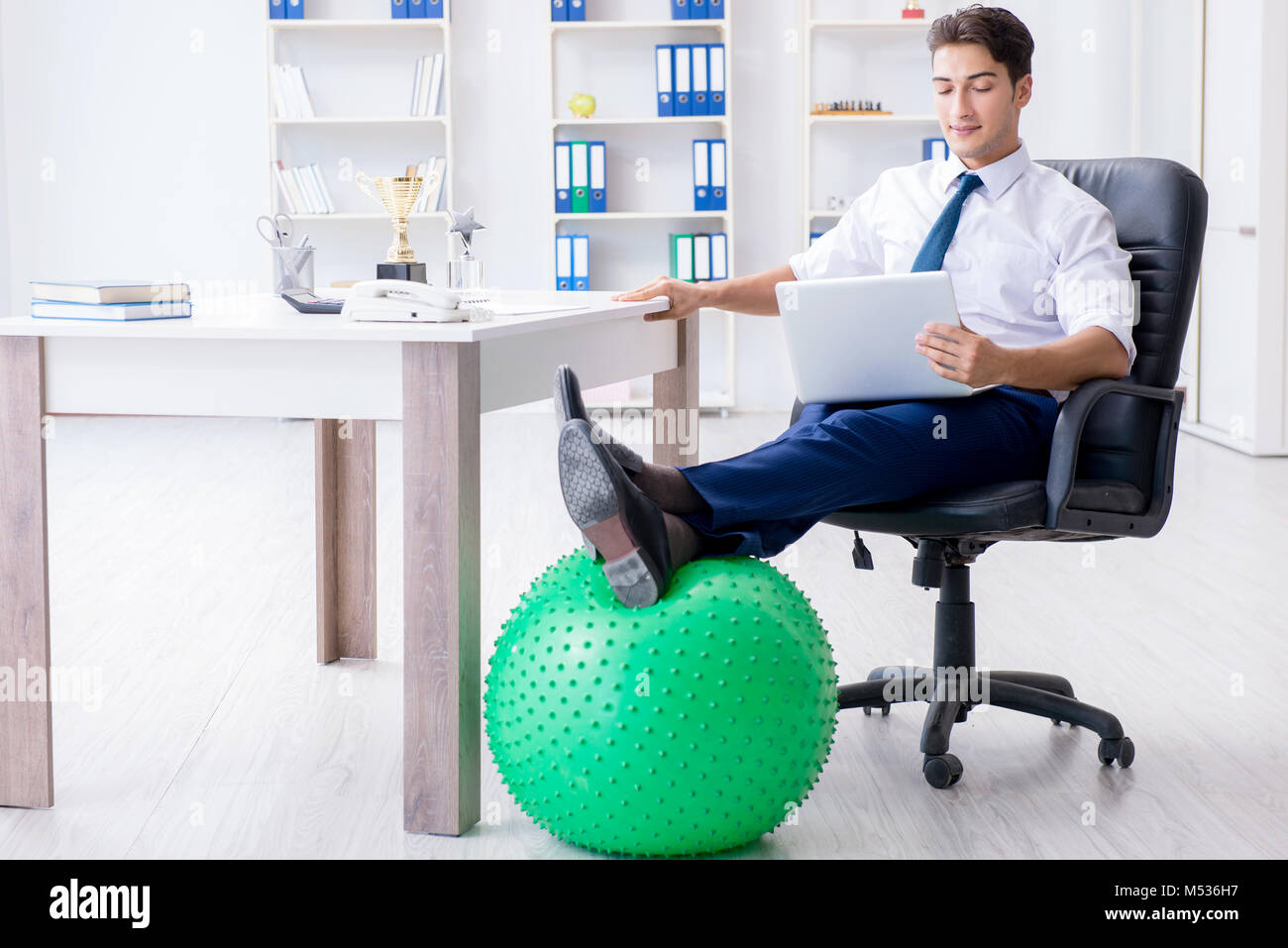 Young businessman doing sports stretching at workplace Stock Photo - Alamy