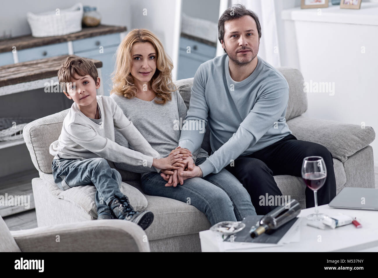 Calm family sitting on the sofa and holding their hands Stock Photo - Alamy