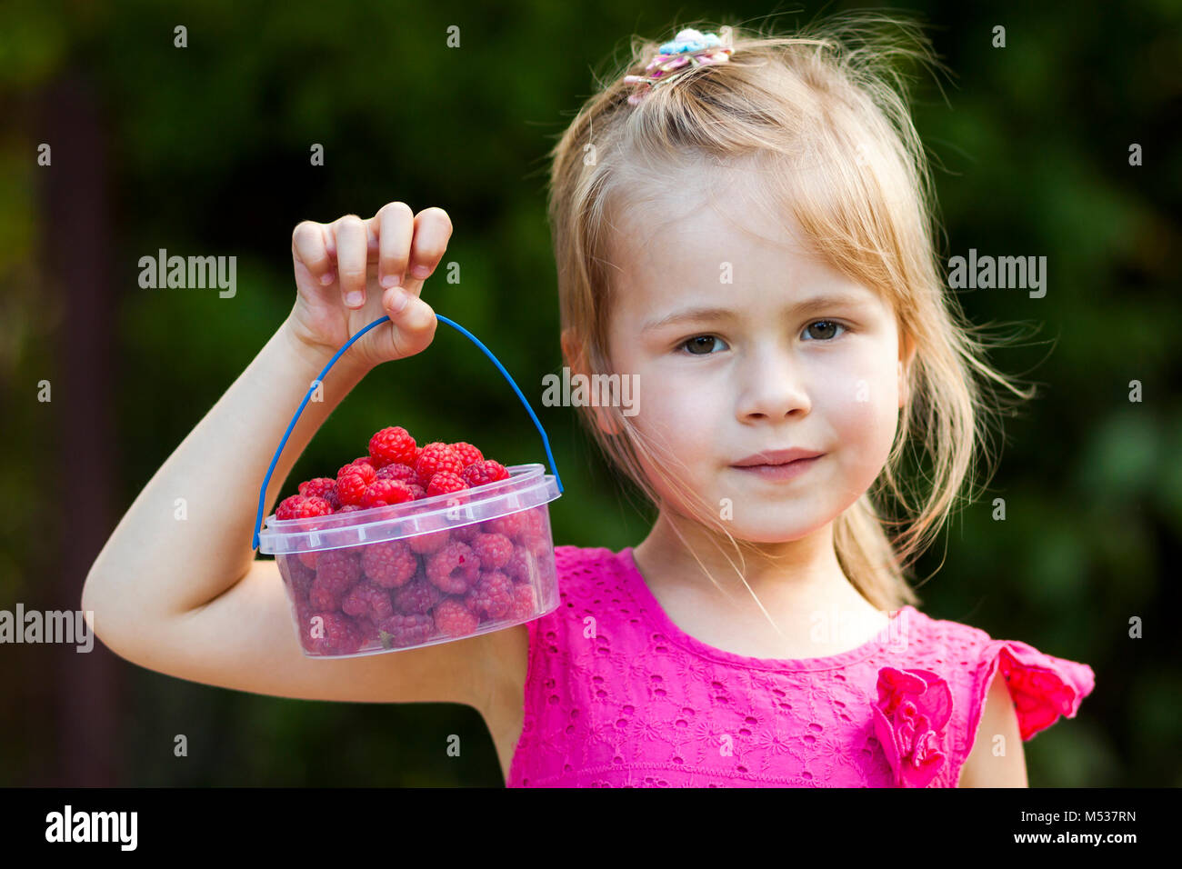Portrait of a little girl child holdind small basket of ripe ...