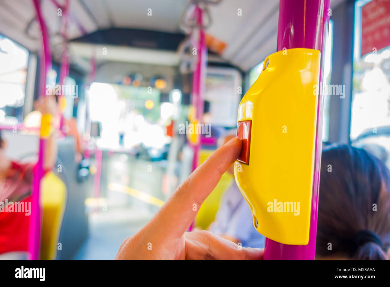 Selective focus of a hand pushing a bus Stop Button inside of the bus ...