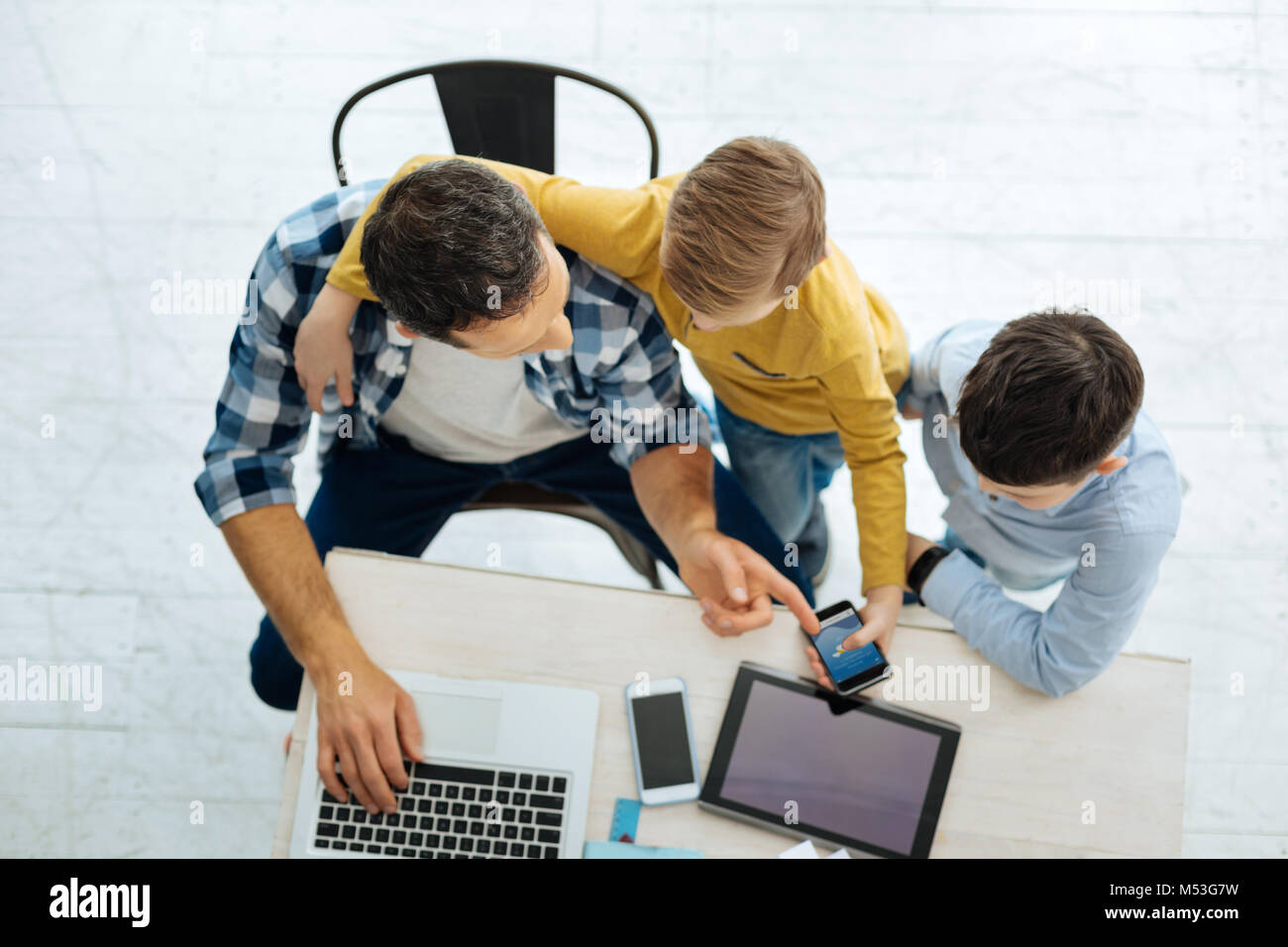 Top view of boys and their father checking weather forecast Stock Photo ...