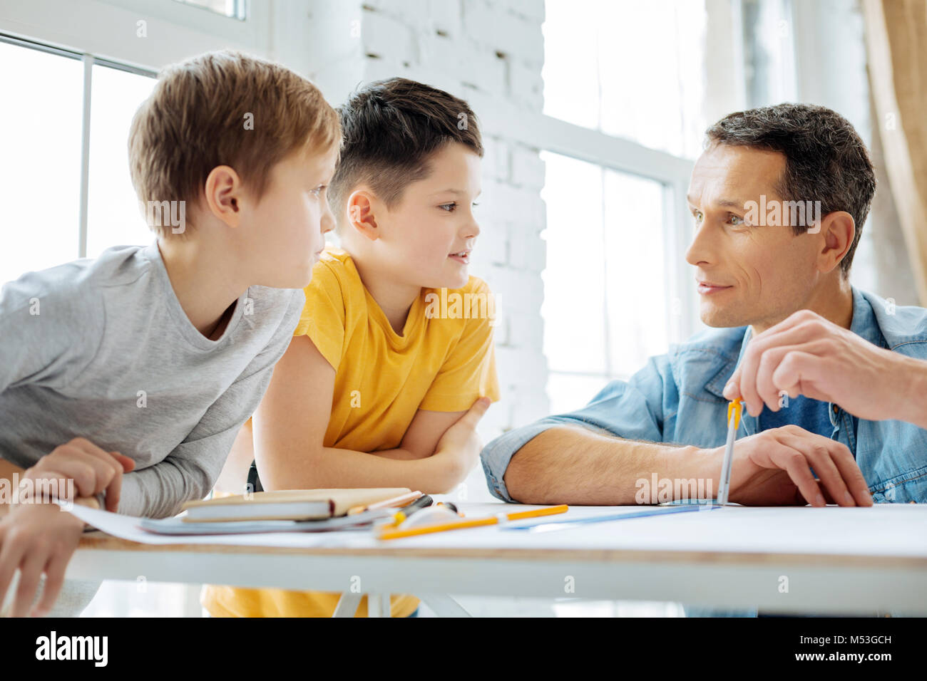 Charming man communicating with children while working Stock Photo - Alamy