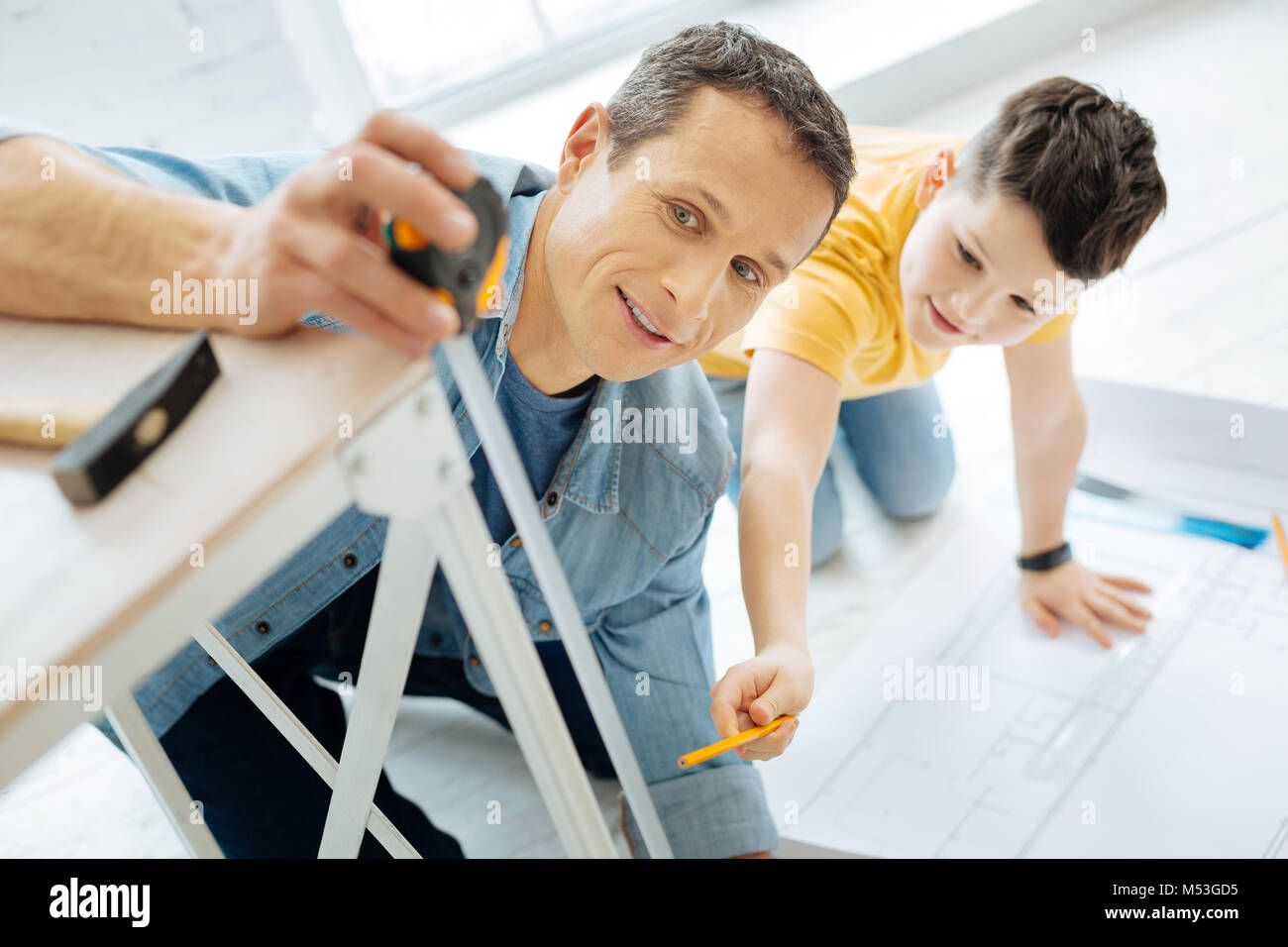 Charming boy helping his father measure table leg Stock Photo - Alamy