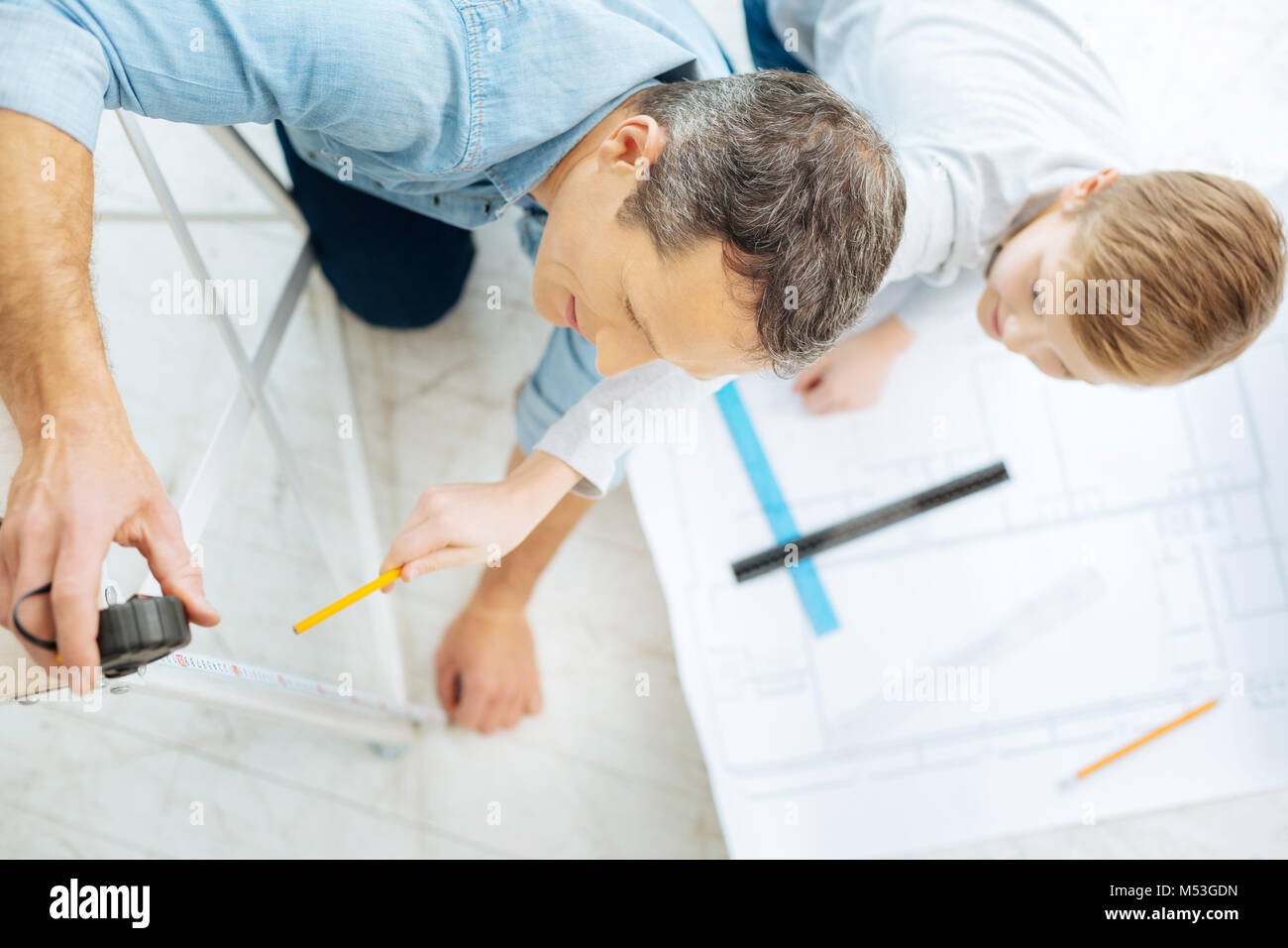Top view of father and son measuring table leg Stock Photo - Alamy